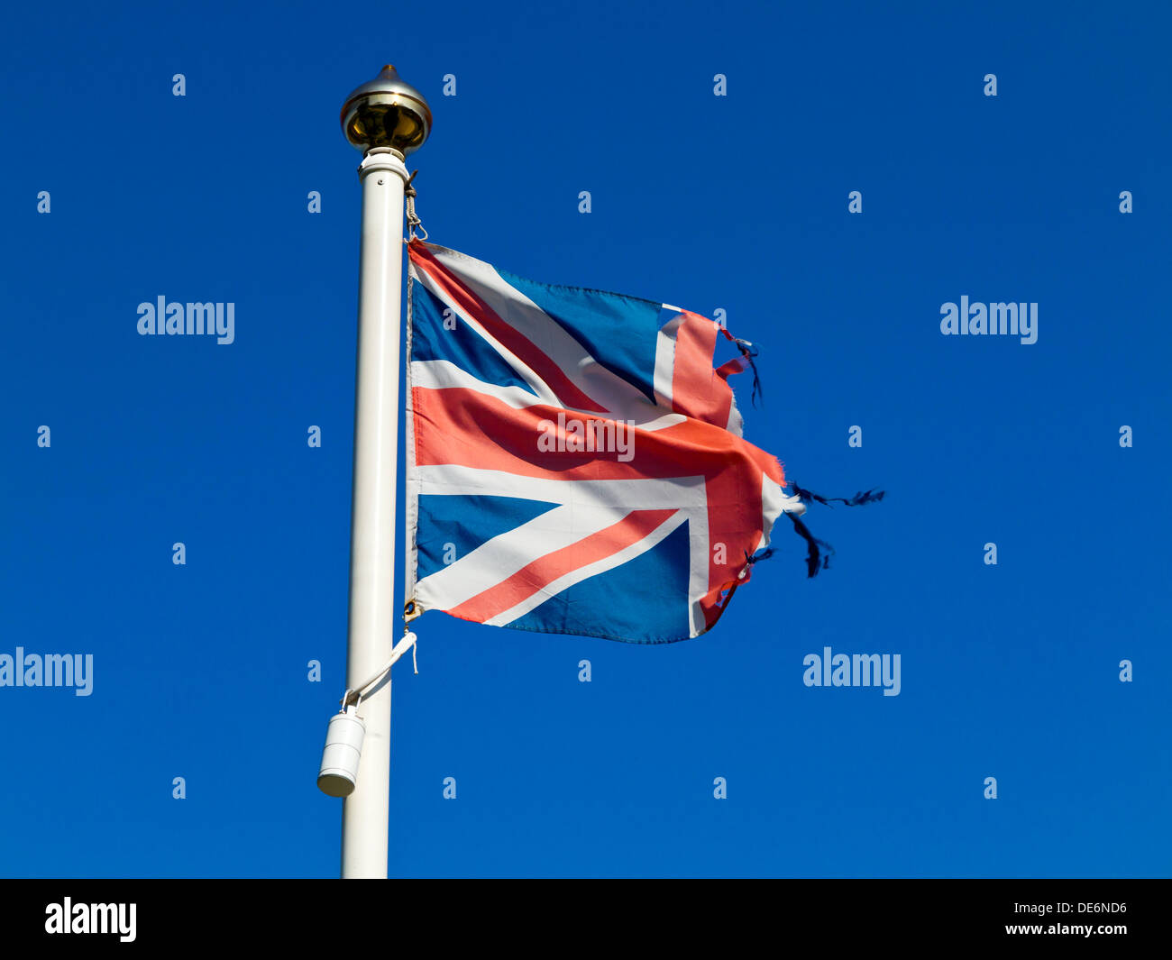 Torn British Union Jack flag on a flagpole with blue sky behind Stock ...