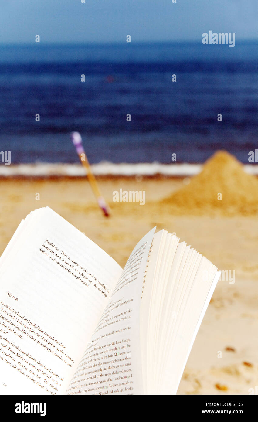 Reading a book on the beach on a summer holiday, Mundesley Beach ...