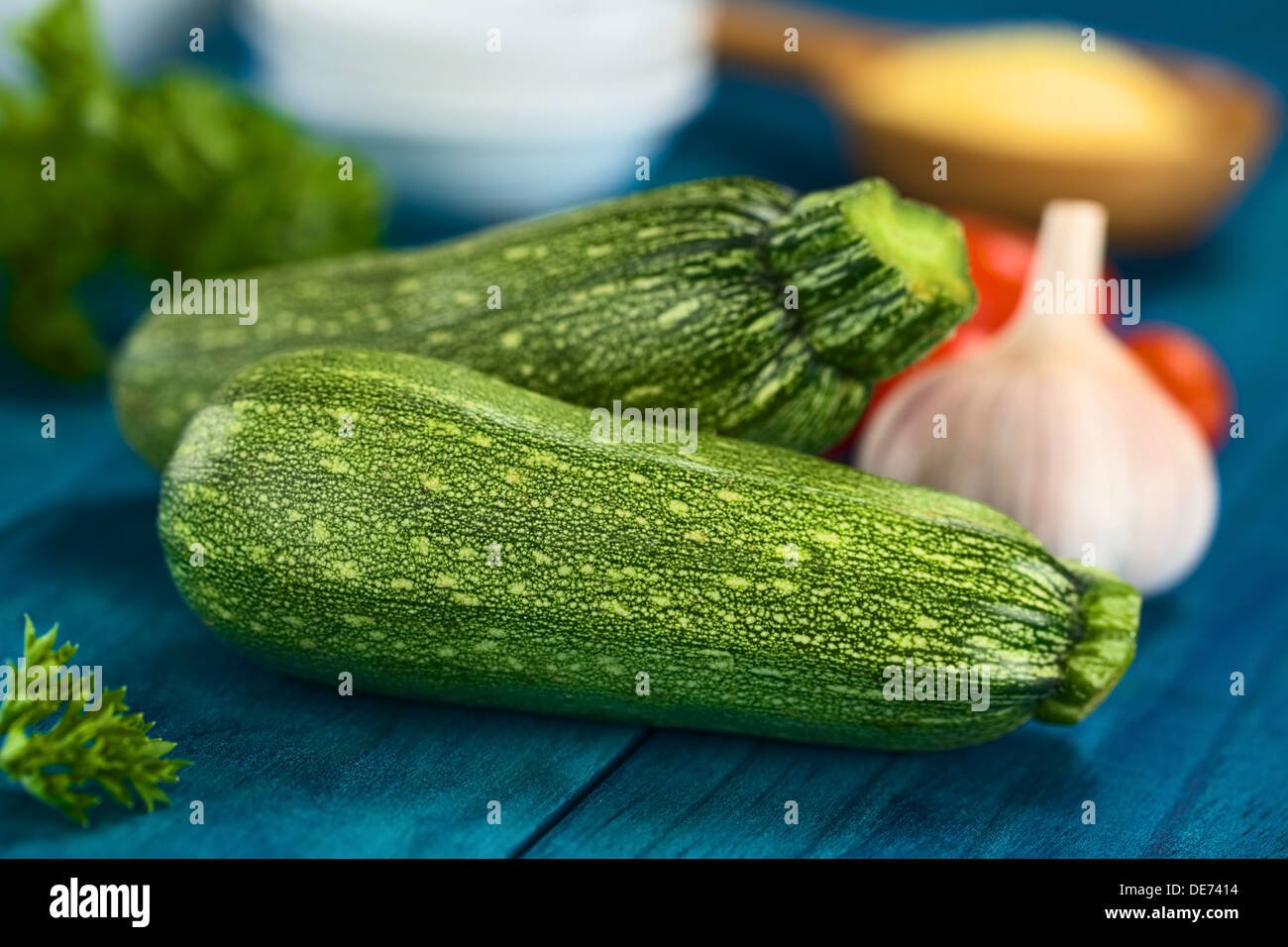 Raw zucchini on blue wood with other ingredients in the back (Selective ...