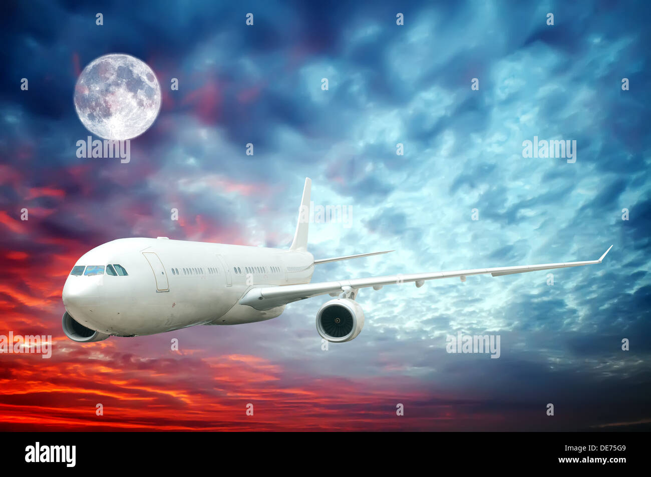 A plane flying high in the nighttime sky with an illuminated moon Stock ...
