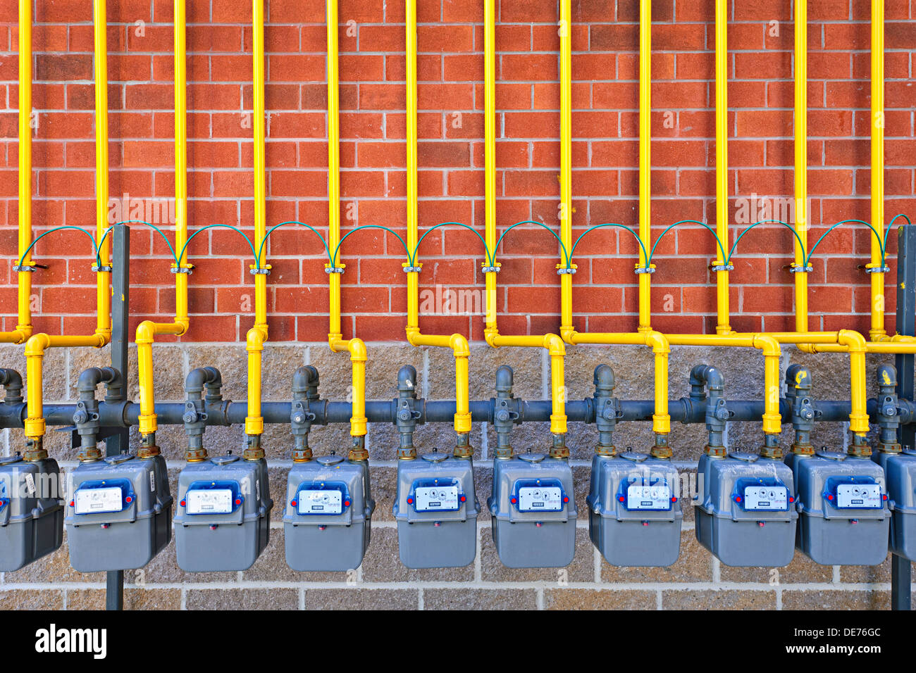 Row of natural gas meters with yellow pipes on building brick wall ...