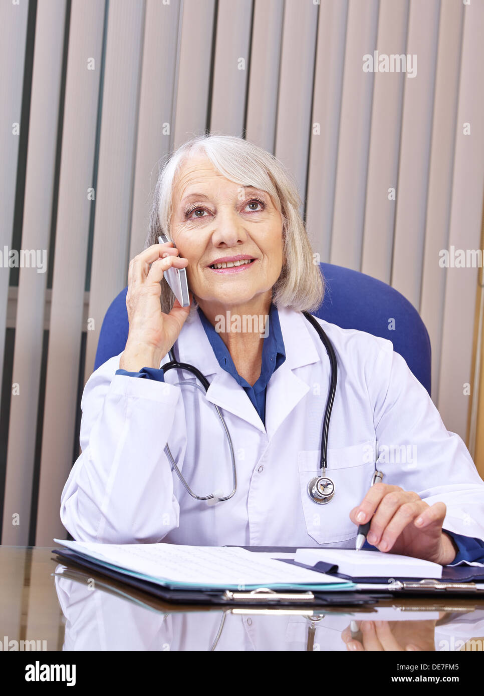 Senior doctor making phone call with smartphone in hospital office ...