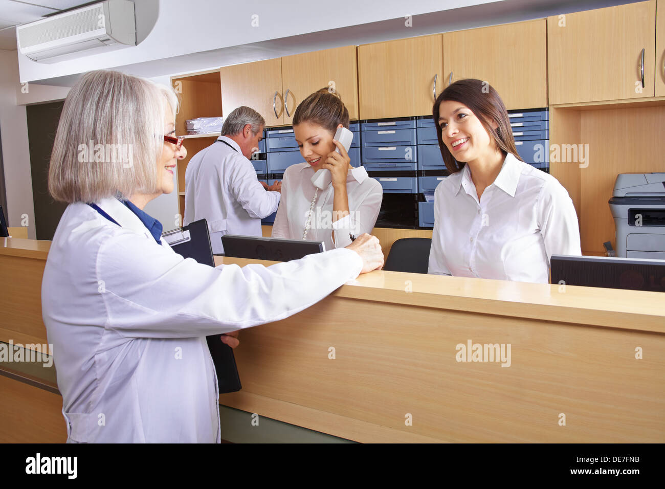 Senior doctor talking with receptionist at hospital reception Stock ...