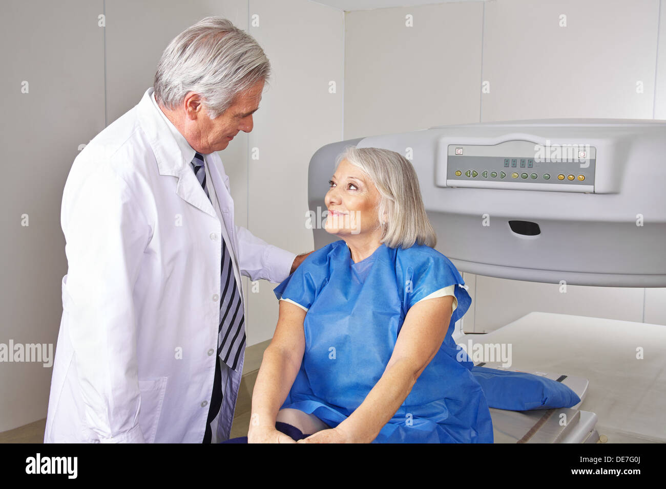 Doctor talking to senior patient prior to bone density measurement in ...