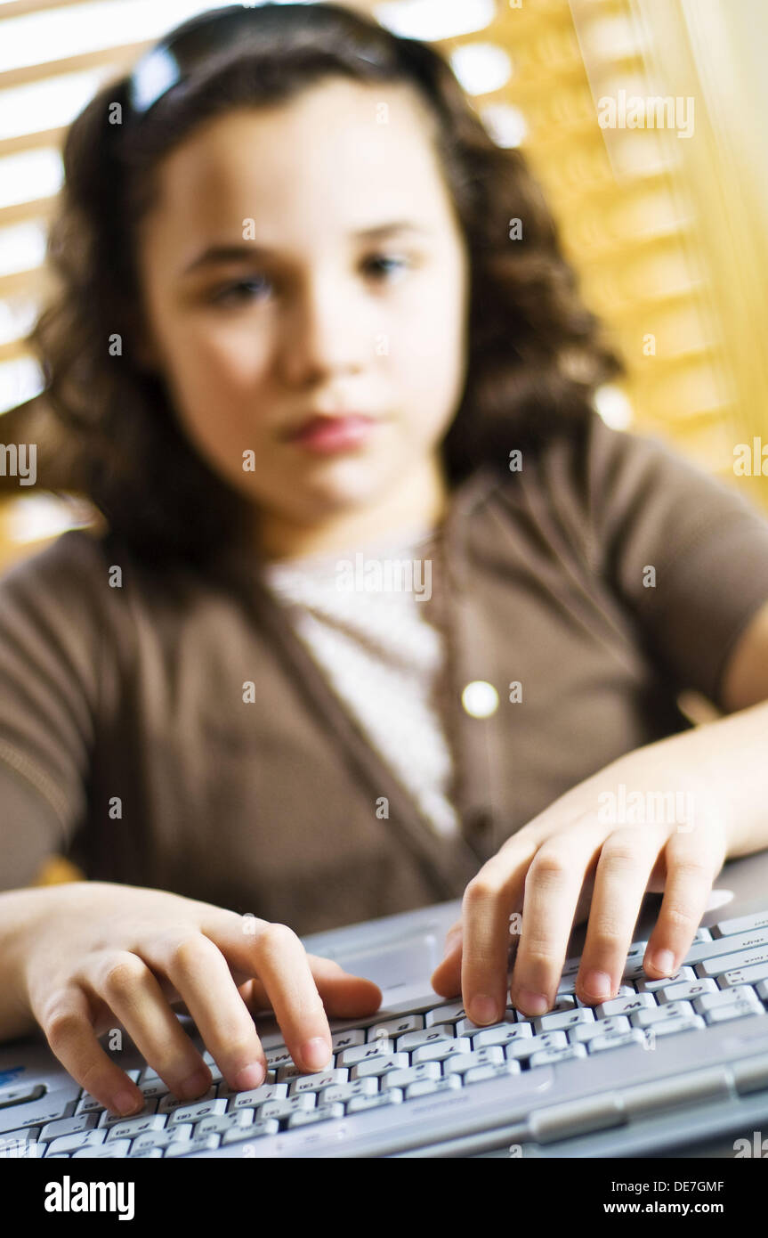Female caucasian brunette child working on a laptop computer sitting at ...