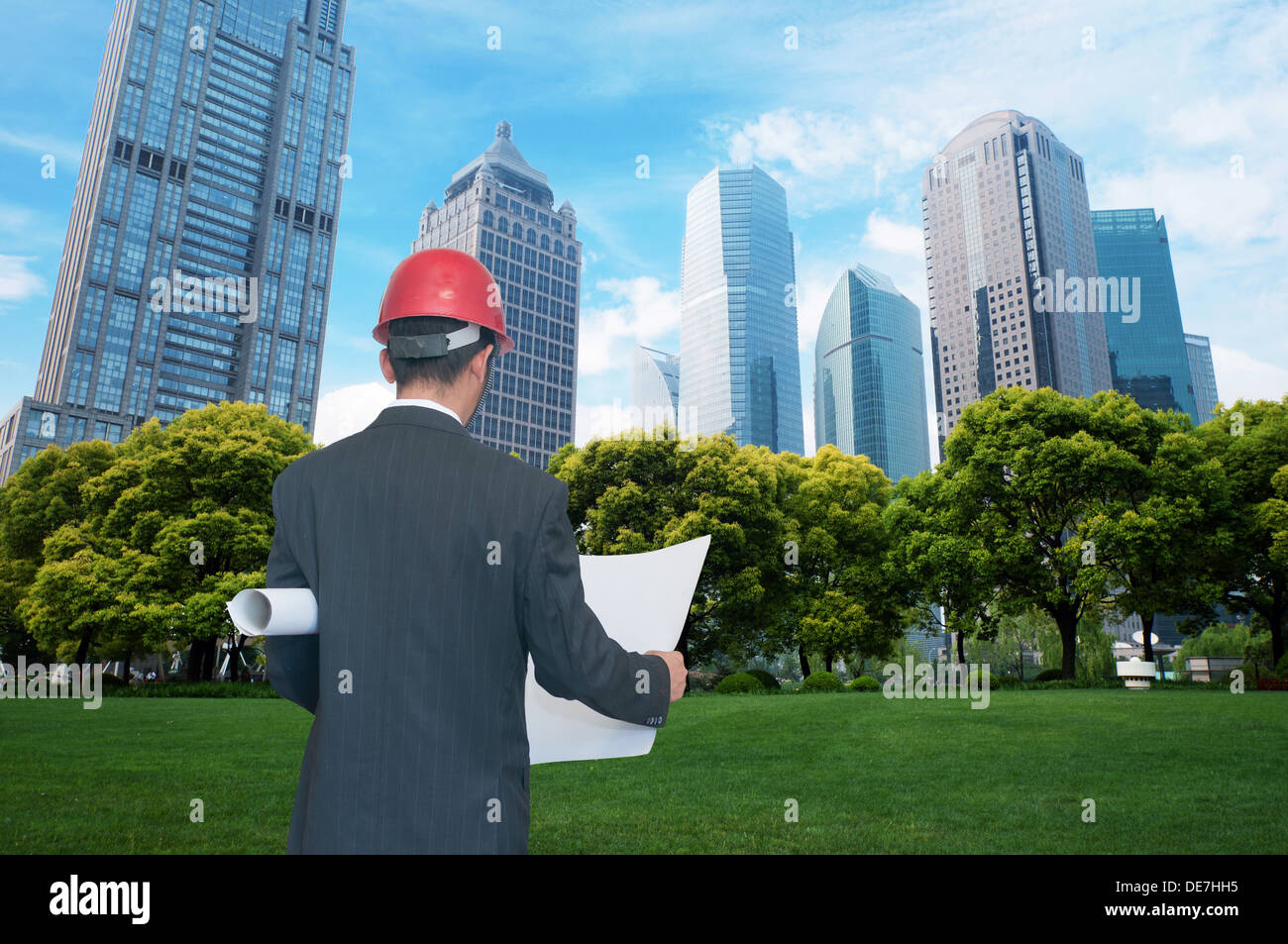 Rear view of architect looking comparing housing project with building ...