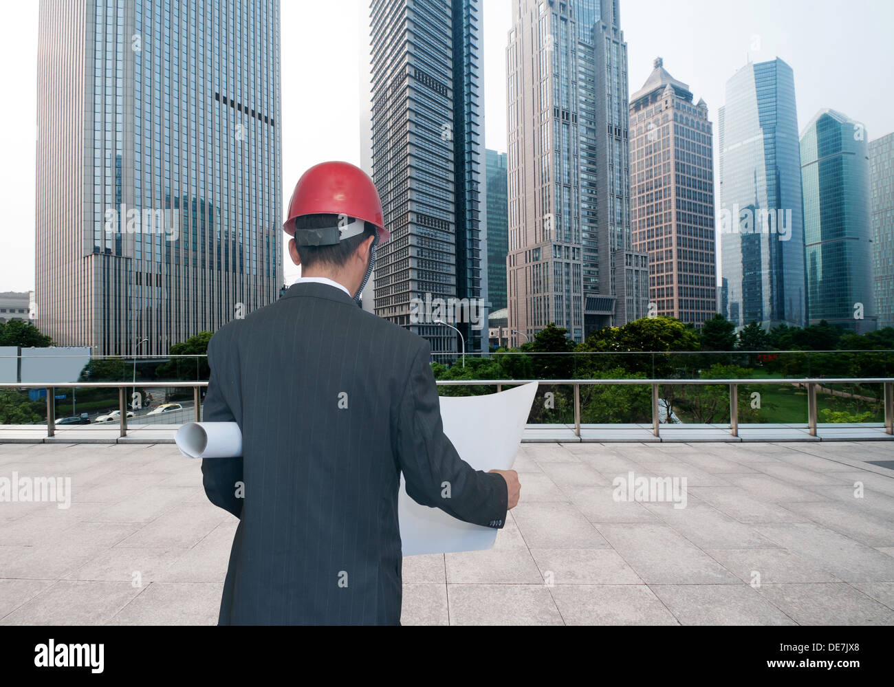 Rear view of architect looking comparing housing project with building ...