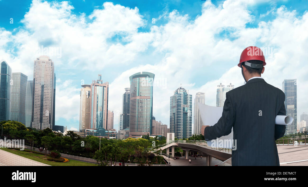 Rear view of architect looking comparing housing project with building ...