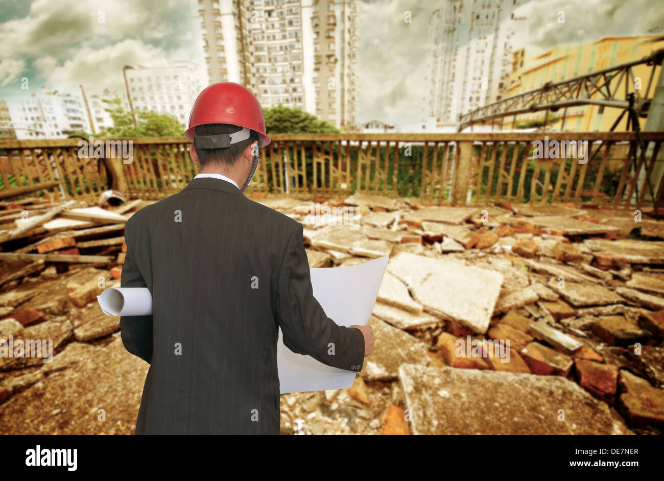 Rear view of architect looking comparing housing project with building ...