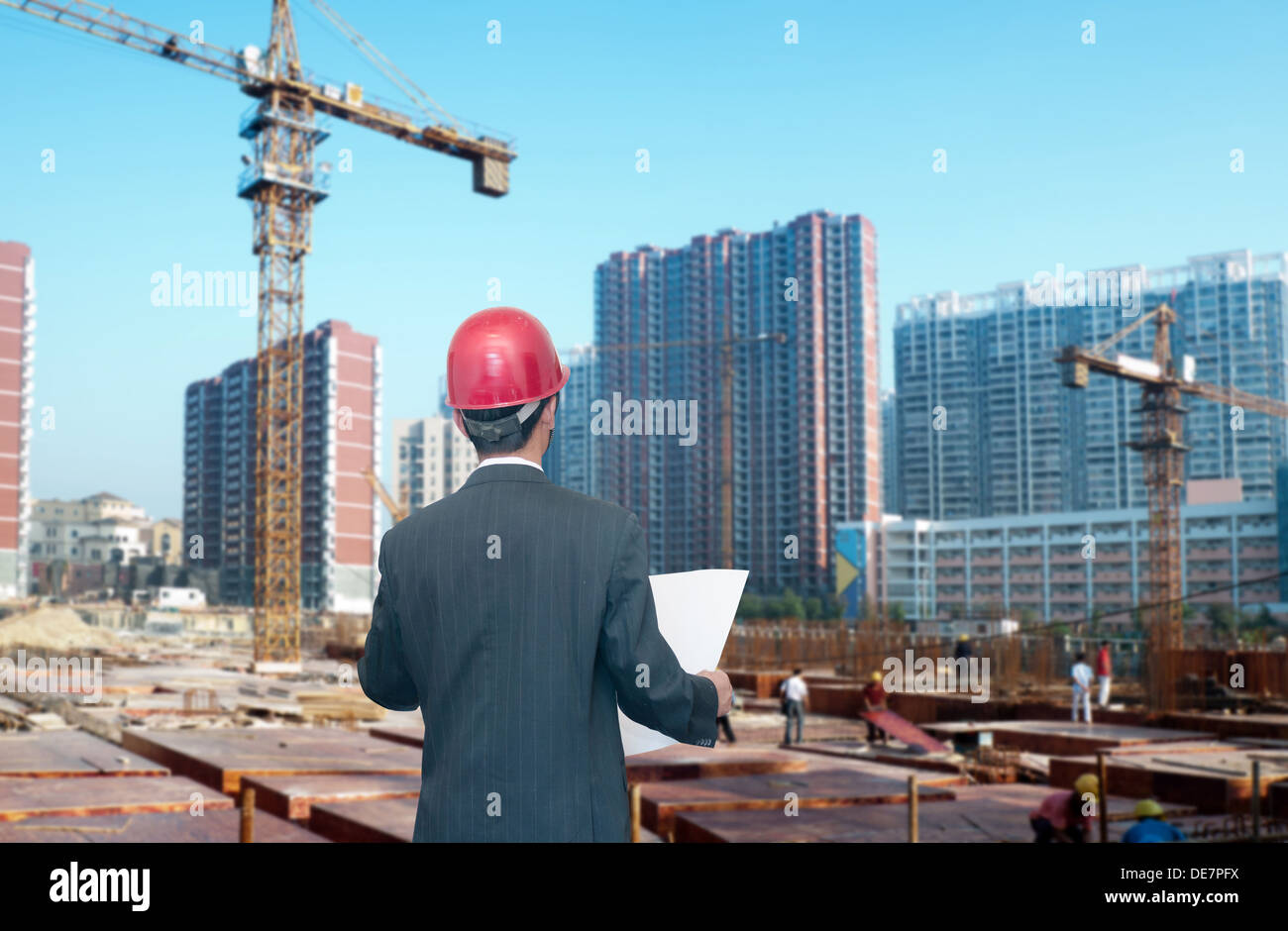 Rear view of architect looking comparing housing project with building ...