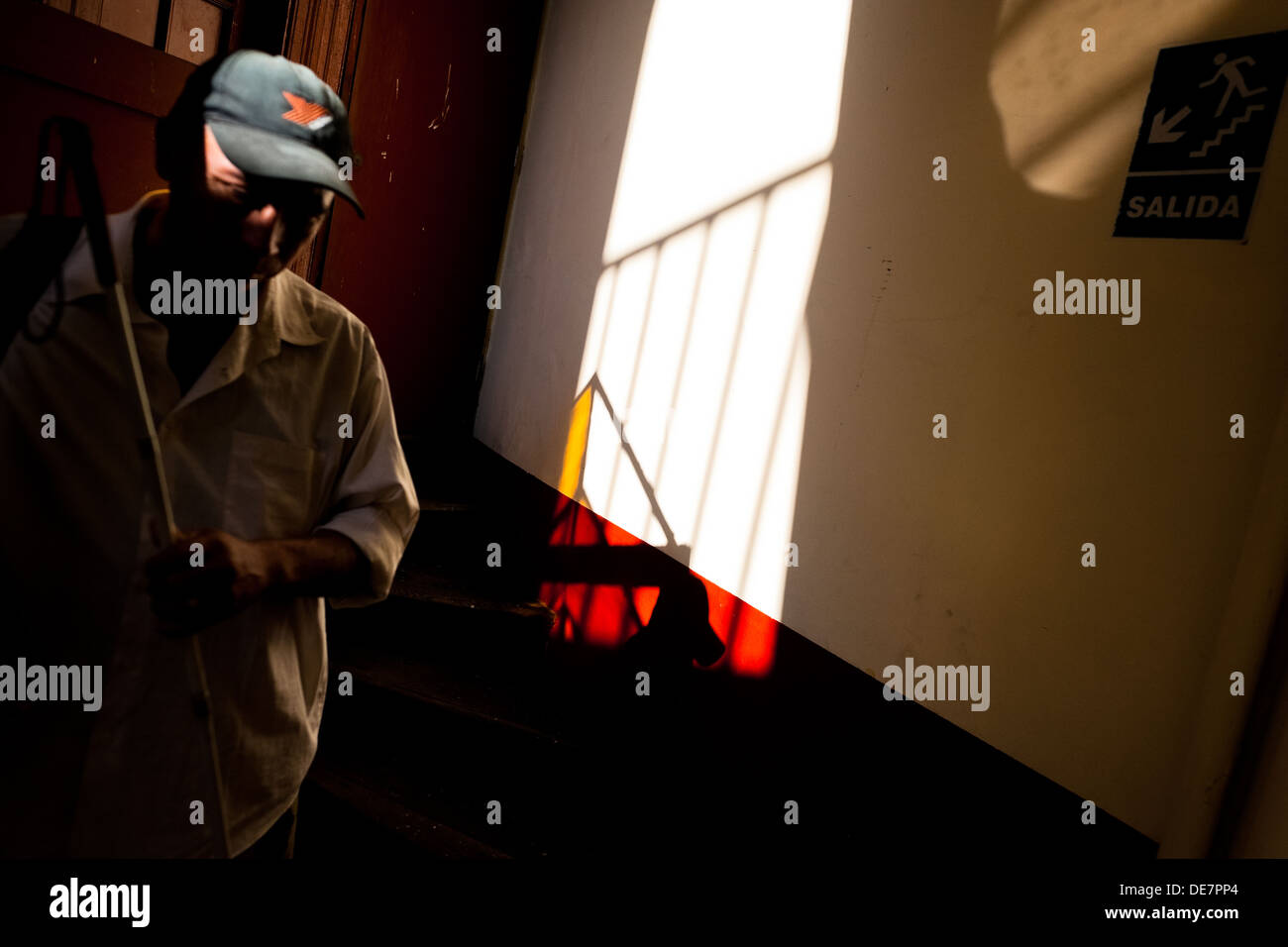 A blind man, using a white cane, finds his way in the corridor of the ...