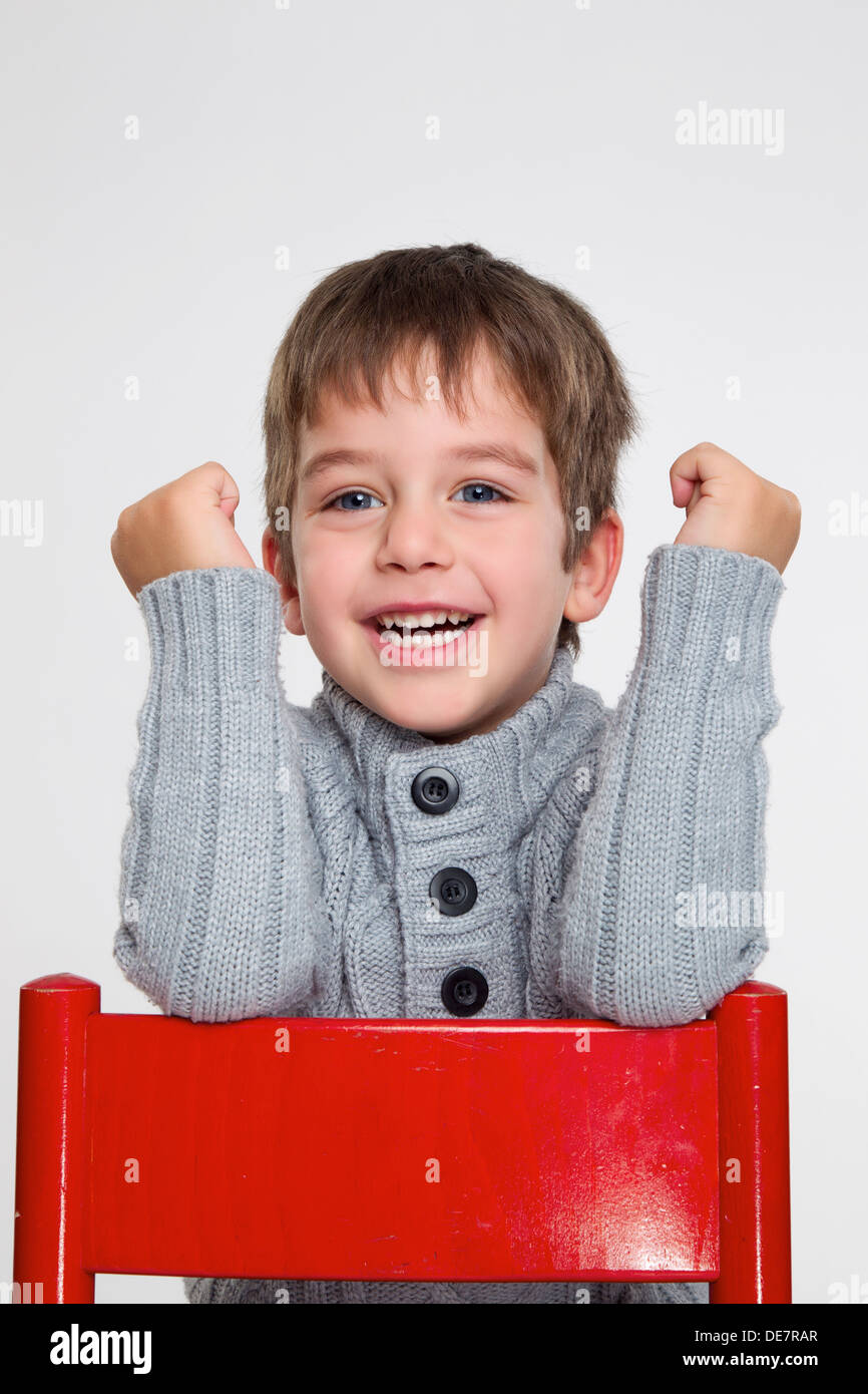 Portrait of boy sitting on red chair, smiling Stock Photo - Alamy