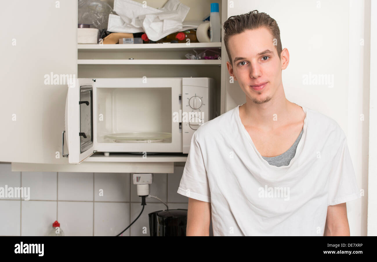 Young man standing in a messy kitchen with open microwave oven Stock ...