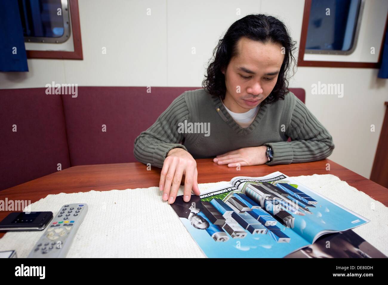 An Indonesian Seaman or sailor, reading a magazine in the galley on the ...