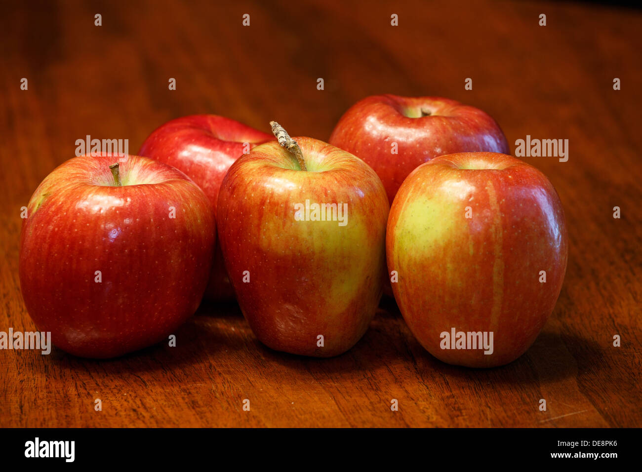 Five red apples on a wood table Stock Photo - Alamy