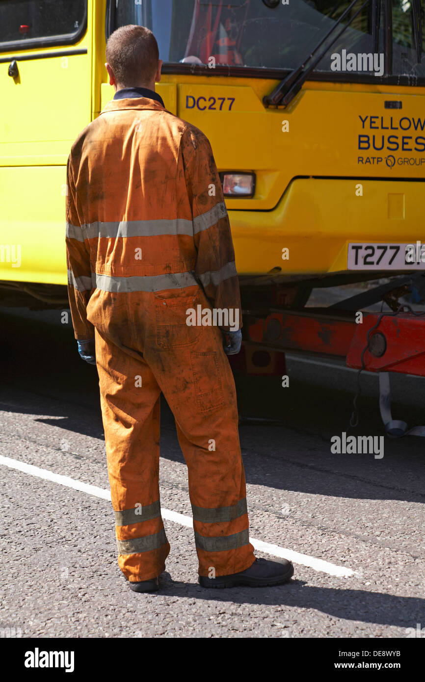 Yellow buses engineer watching bus being prepared for towing away by ...