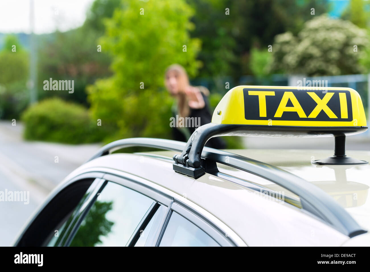 Young businesswoman waiting for a taxi stopping the driver waving from ...