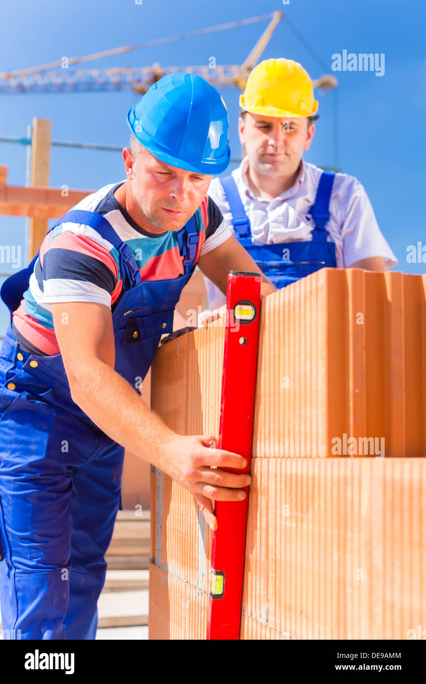 Construction site workers or bricklayer with helmets controlling ...