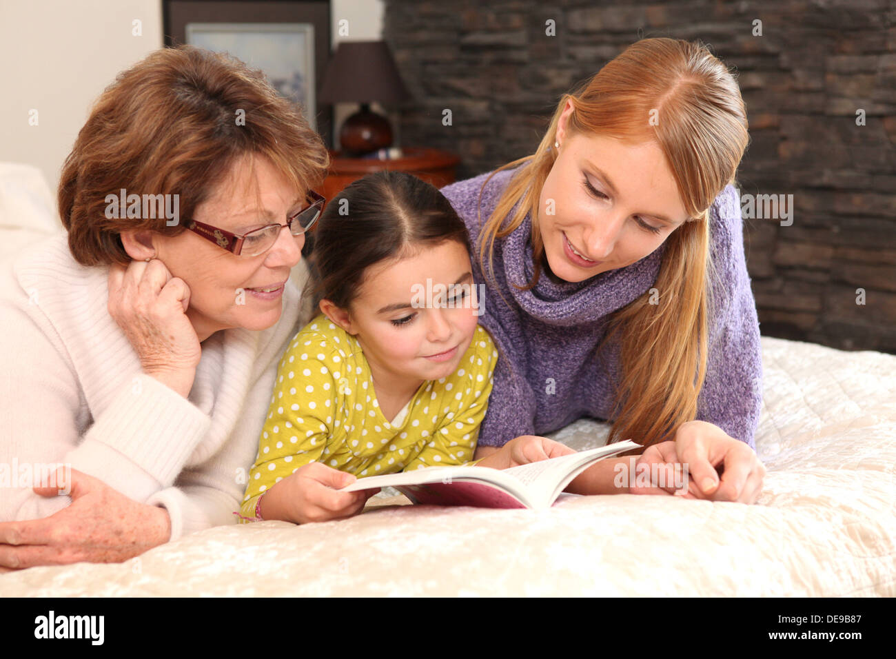 Three generations reading a book together Stock Photo - Alamy
