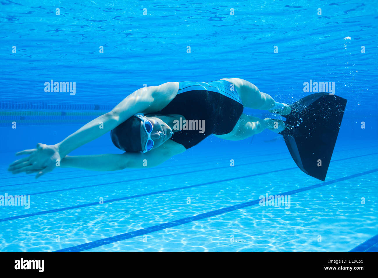 Female freediver with monofin swimming underwater in swimming pool in ...