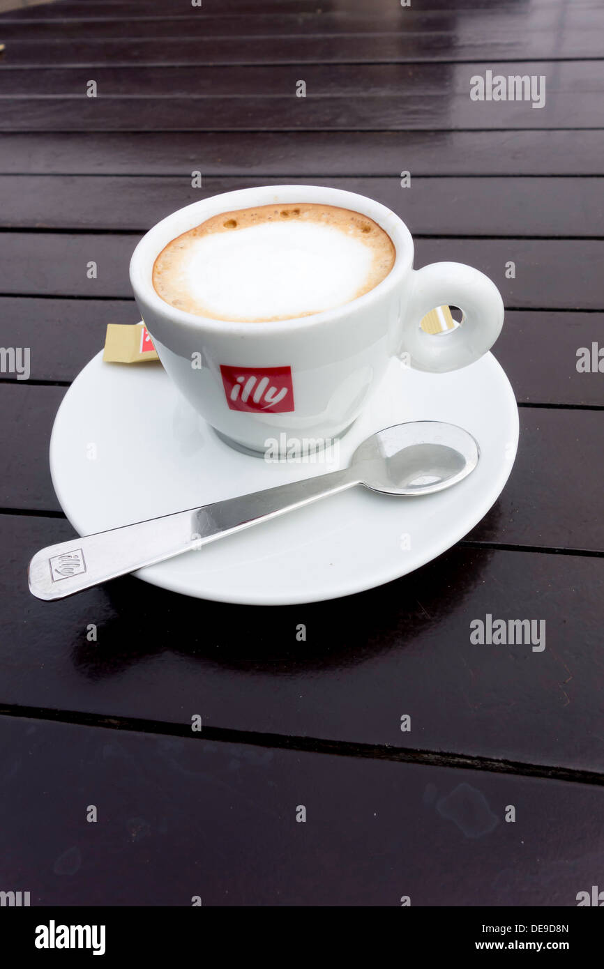 A cup of Illy brand Macchiato coffee on an outdoor terrace cafe table ...