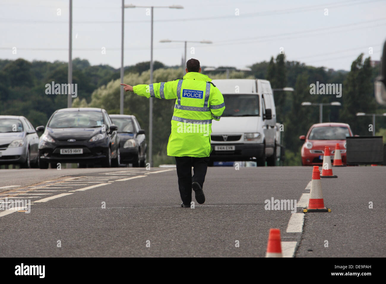 A police officer directs traffic away from an accident scene on a busy ...