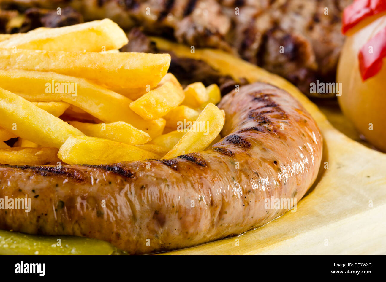 Rustic tray with various meats, french fries and assorted vegetables ...