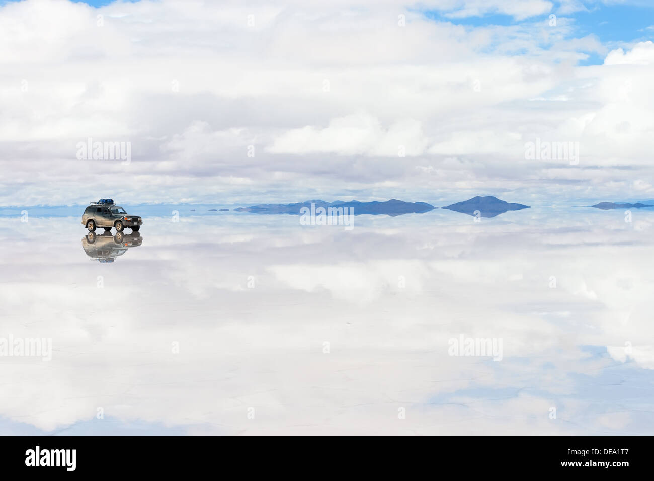 Off-road car on reflected surface of lake Salar de Uyuni in Bolivia ...
