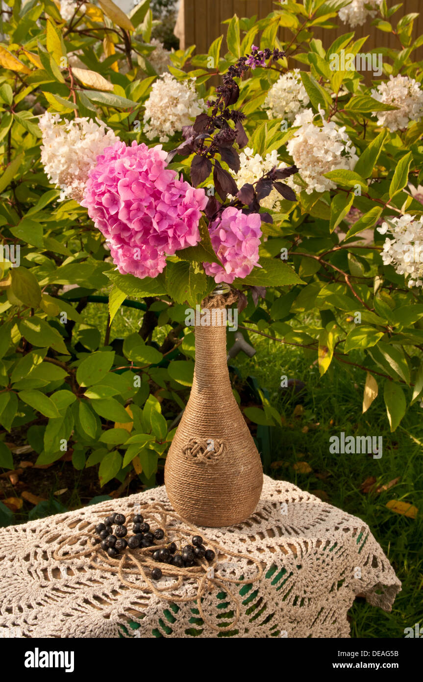 still life with pink hydrangea in a vase and white hydrangea plant as a ...