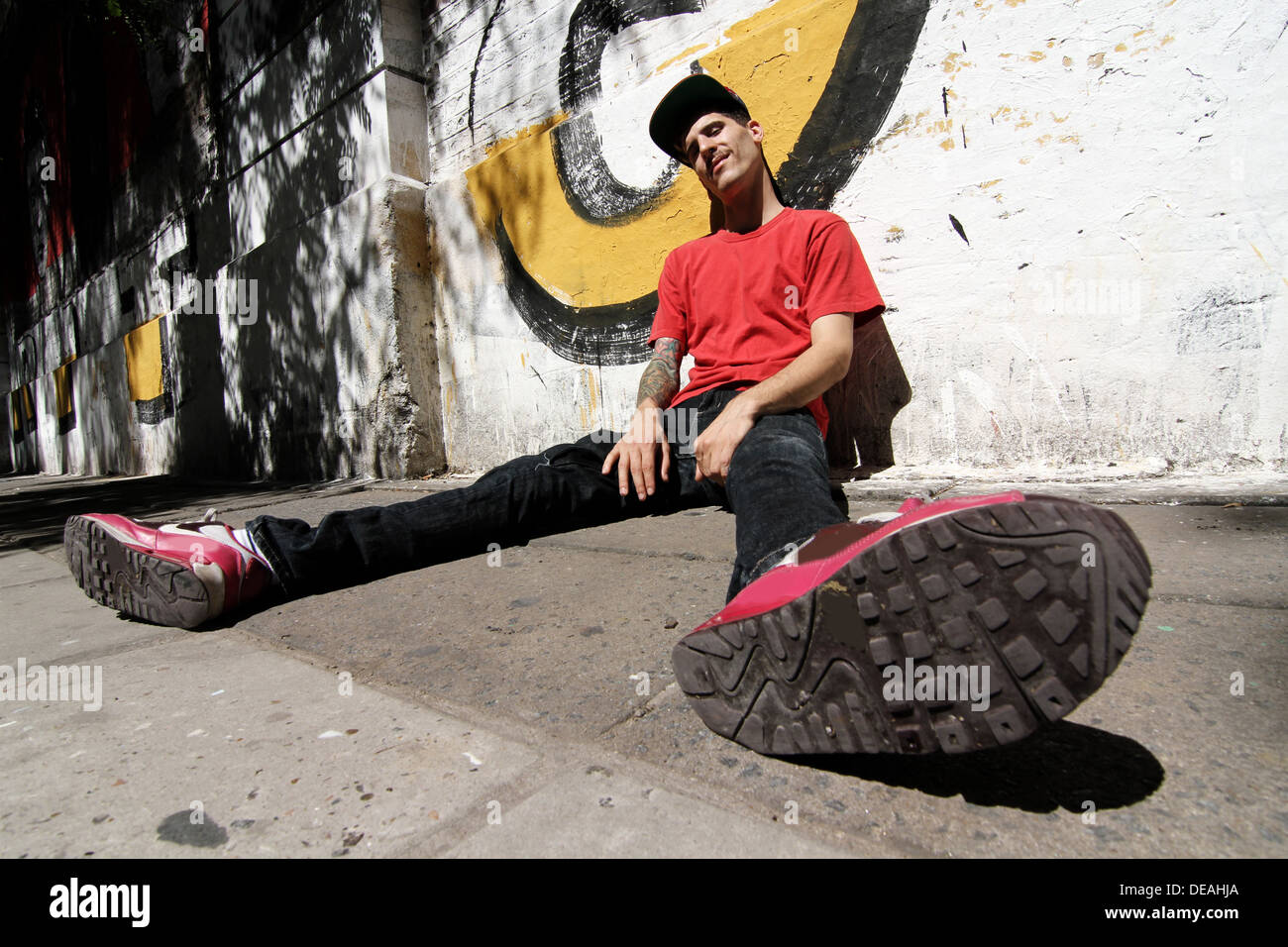 A Rapper leaning against a Graffiti wall Stock Photo - Alamy