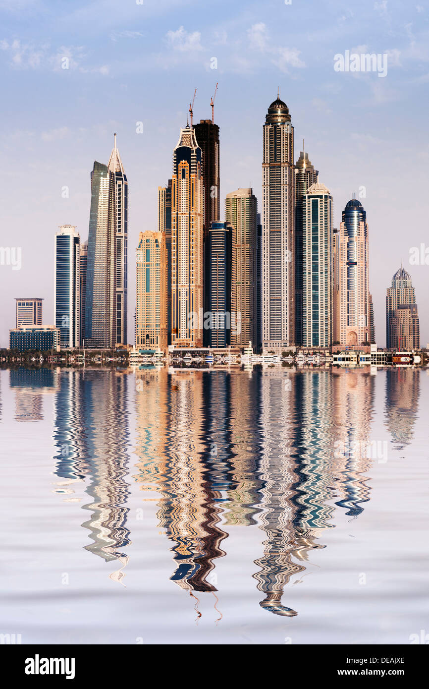 Modern skyline of new Dubai with many skyscrapers reflected in sea in ...