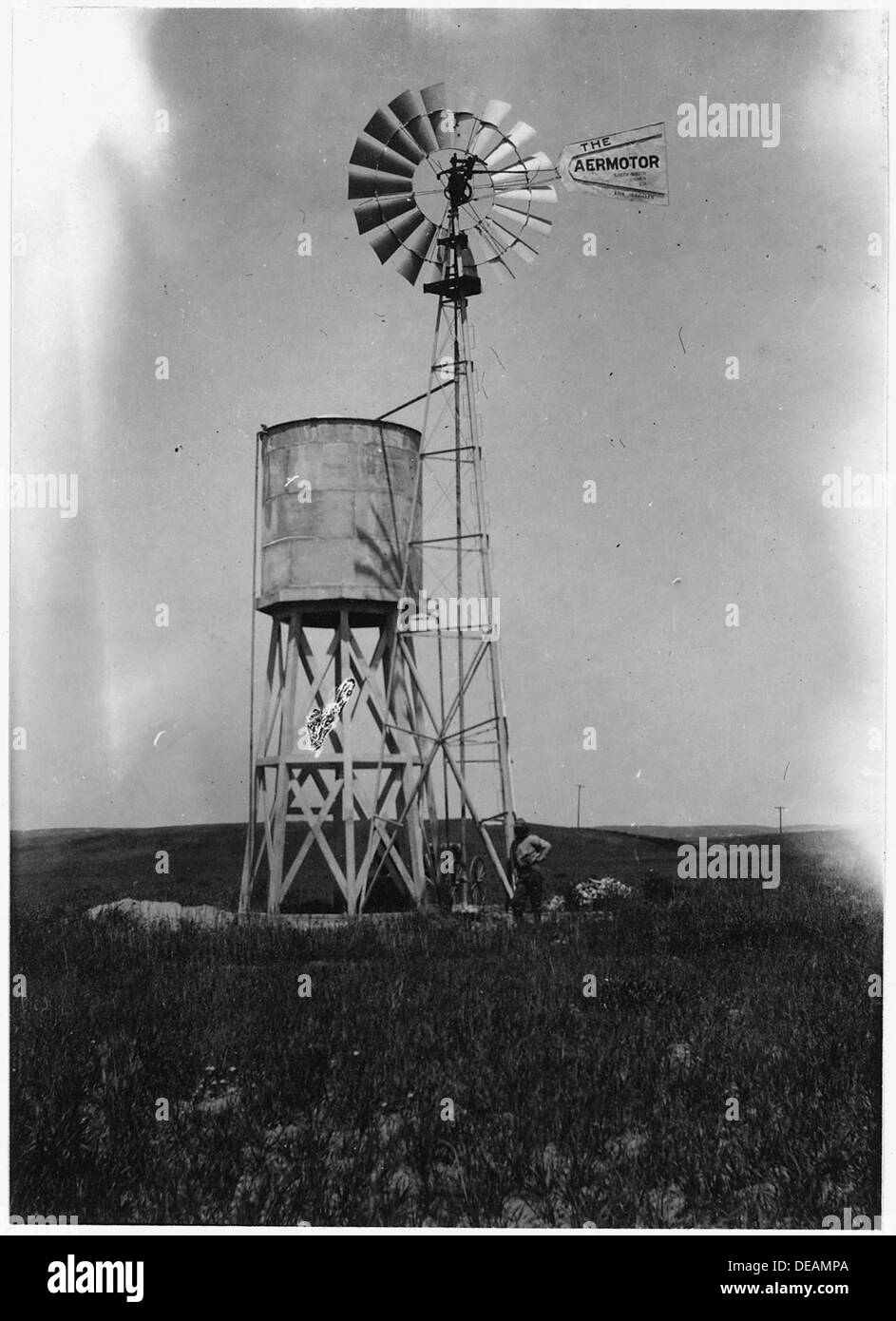 The photograph shows a windmill and water tank in Pachanga, a rural ...