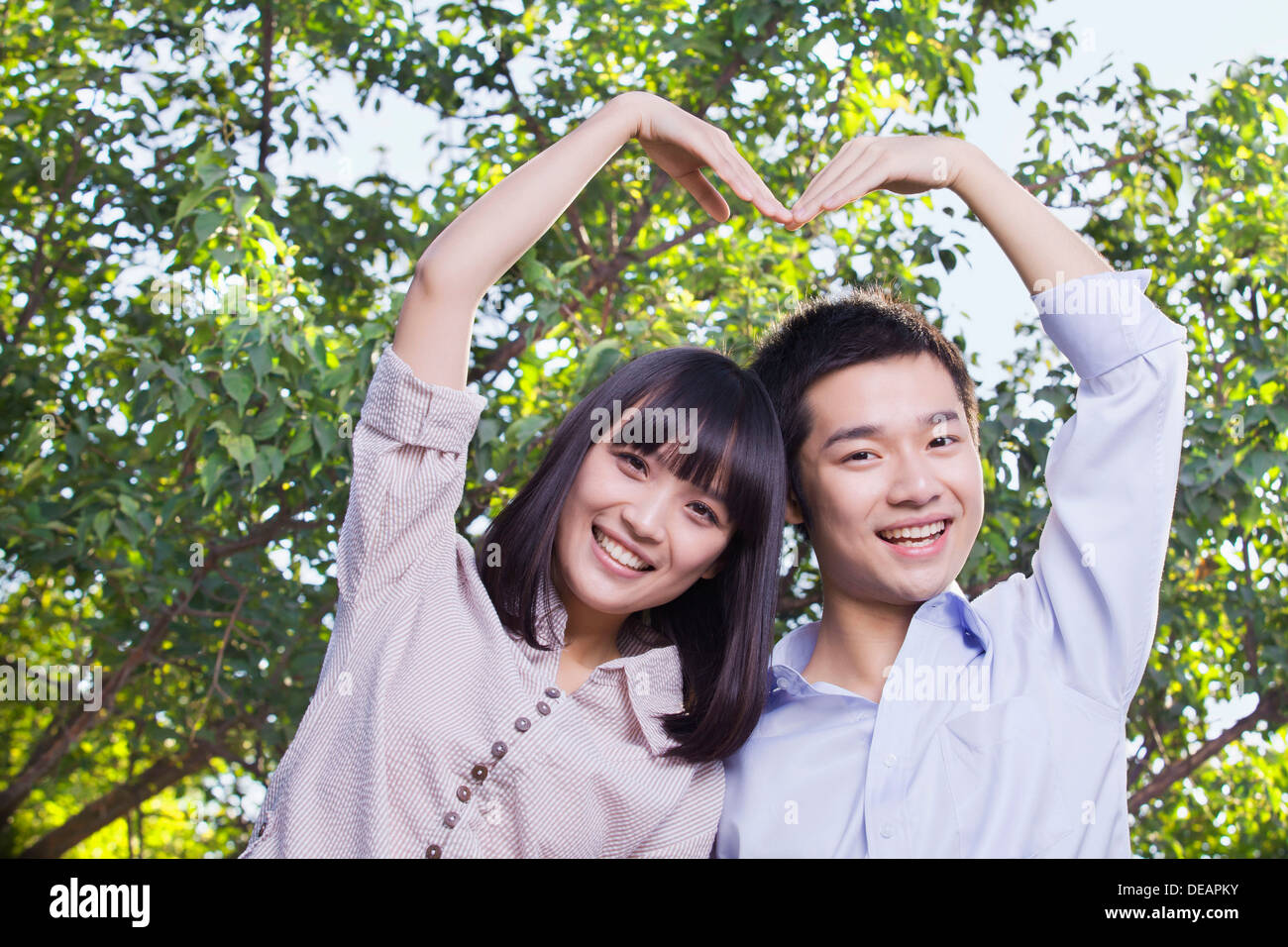 Young Couple Making a Heart Shape with Their Arms Stock Photo - Alamy
