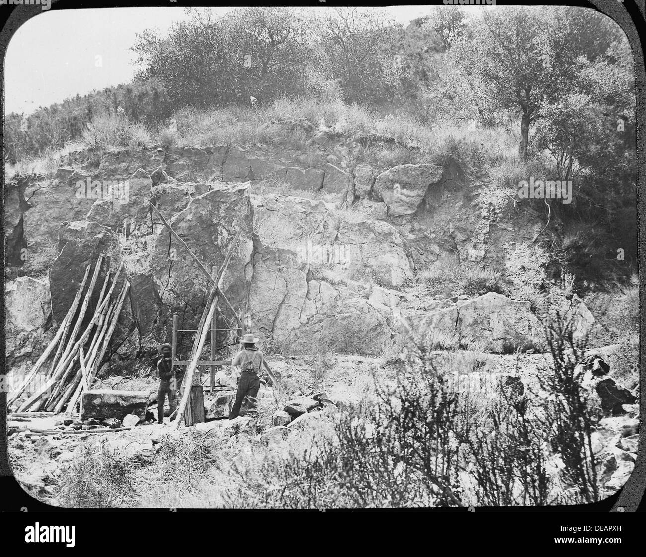 A photograph showing two men beginning to work in a vertical mine shaft ...
