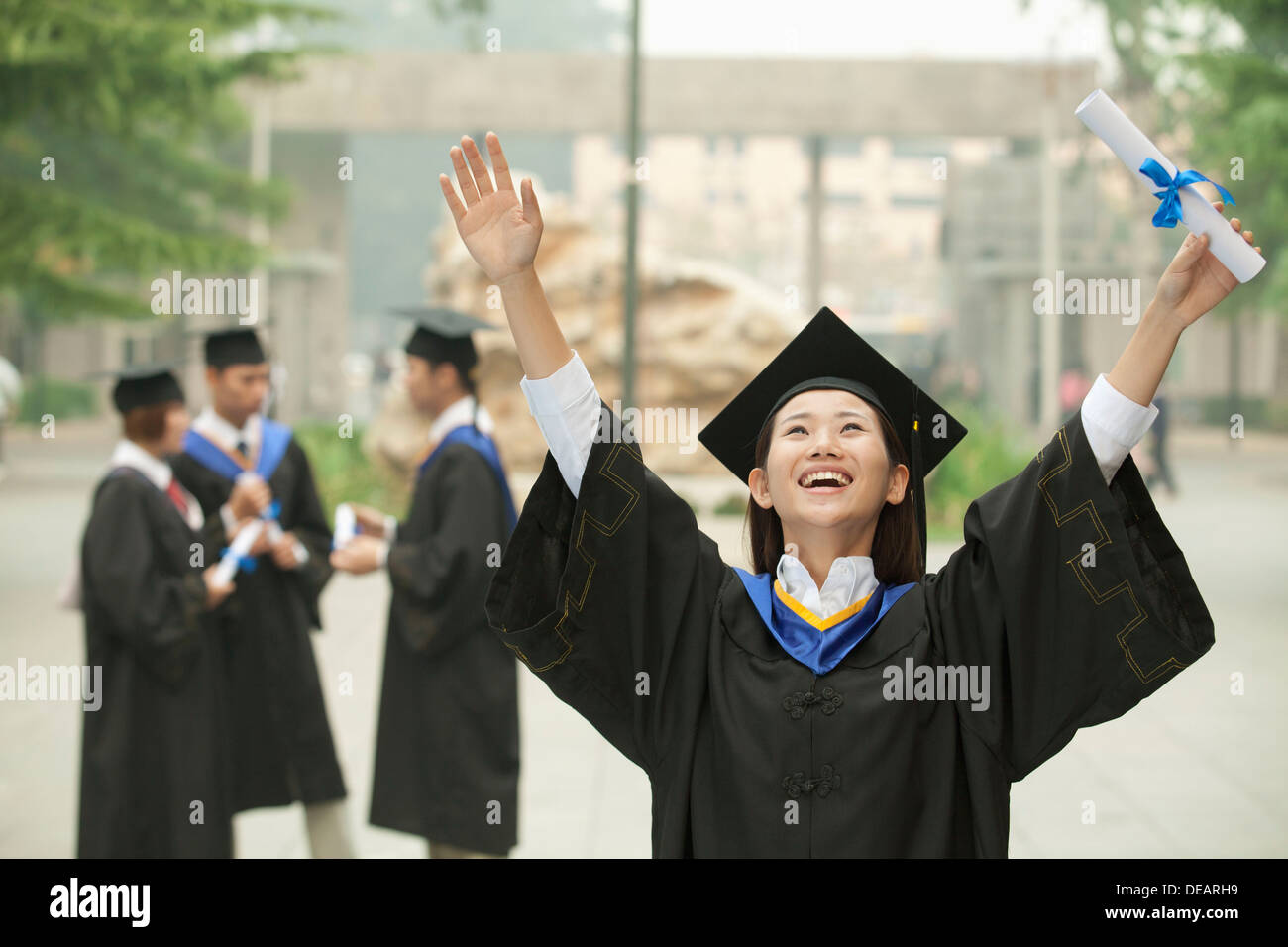Young Female University Graduate, Arms Raised in the Air with Diploma ...
