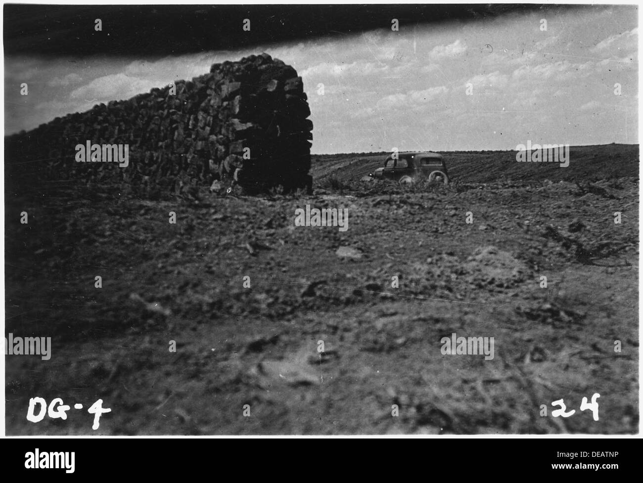 A car is positioned in an excavated reservoir, with piles of dirt ...