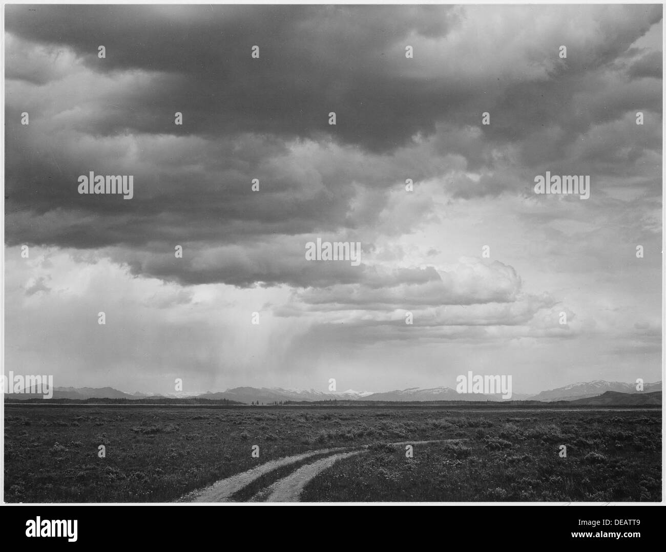 A photograph of a roadway with a low horizon, mountains in the distance ...