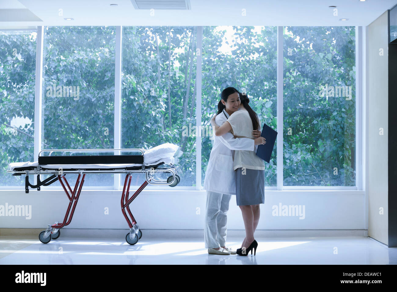 Doctor and patient hugging in a hospital next to a stretcher, full ...
