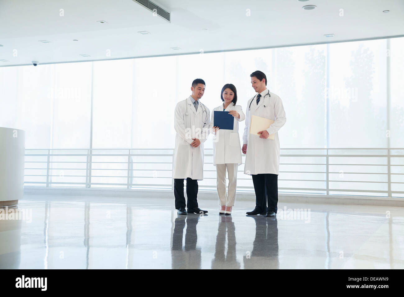 Three doctors standing and looking down at a document in the hospital ...