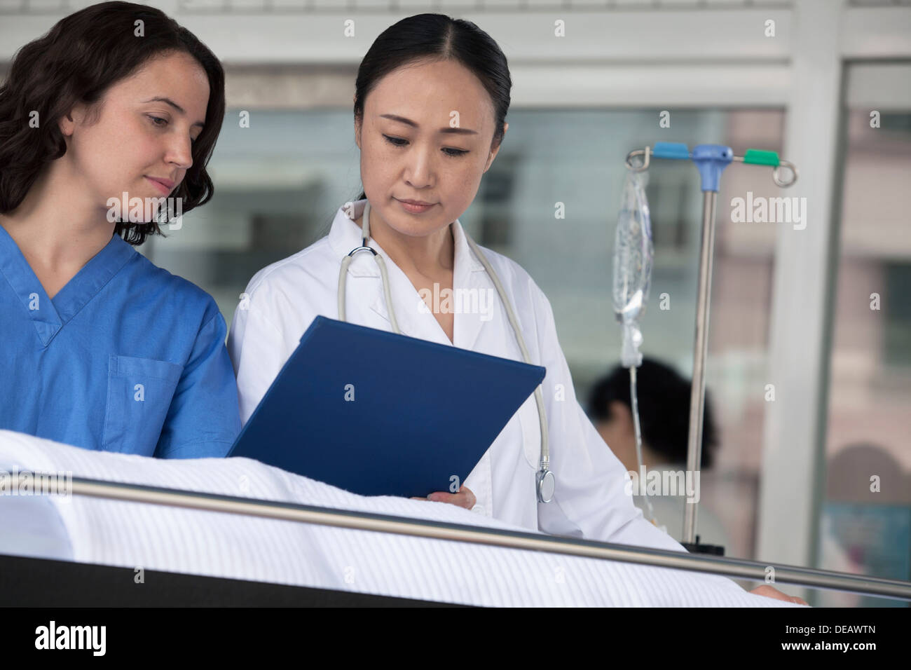Paramedic and doctor looking down at the medical record of patient on a ...