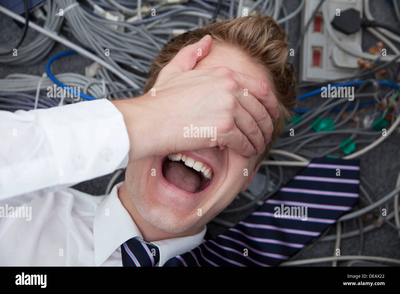 Frustrated man lying down covering his eyes surrounded by computer ...