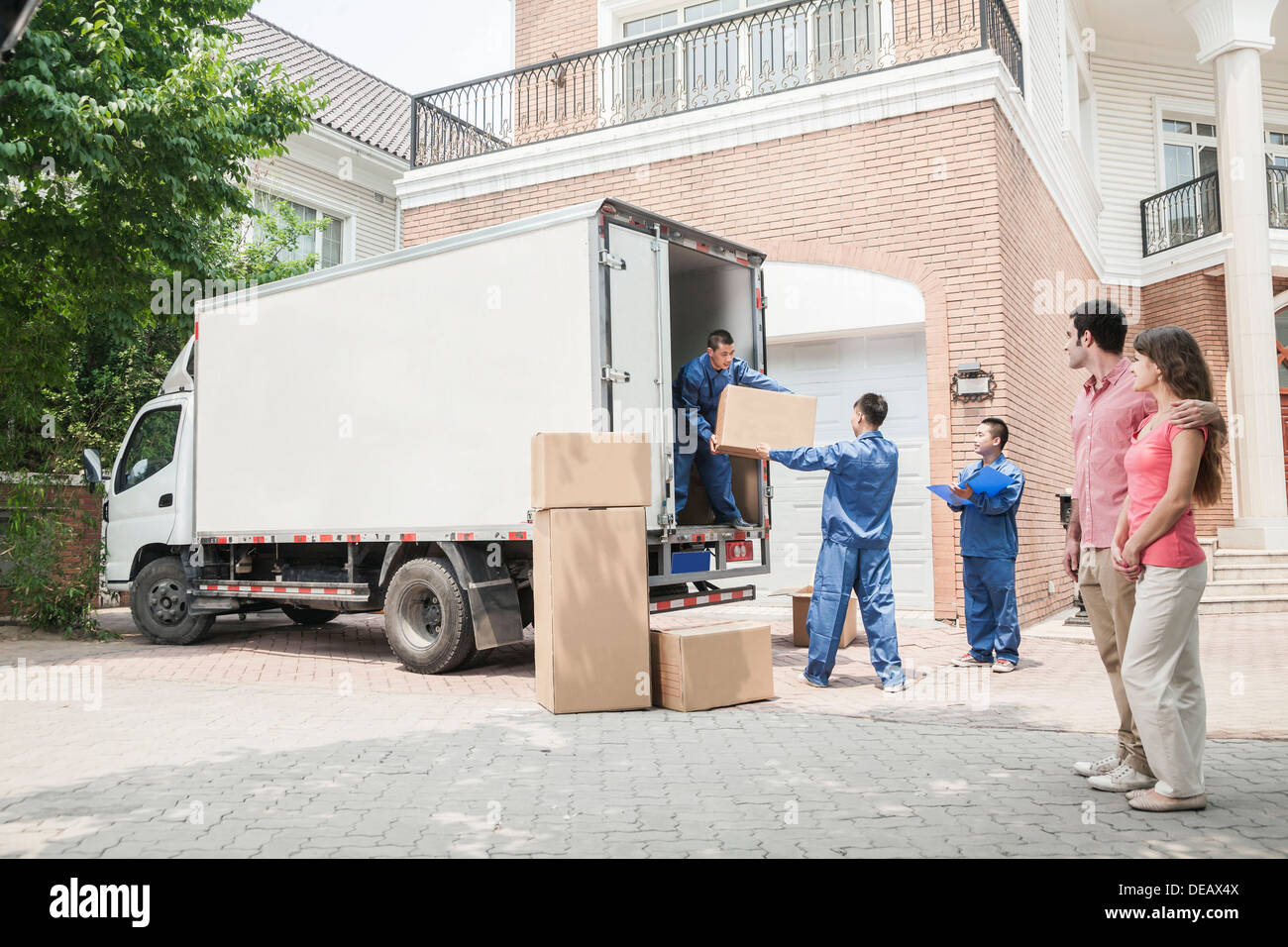 Young couple watching movers move boxes from the moving van Stock Photo ...