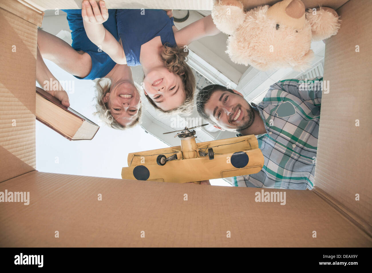 Smiling family looking into a cardboard box, view from directly under ...