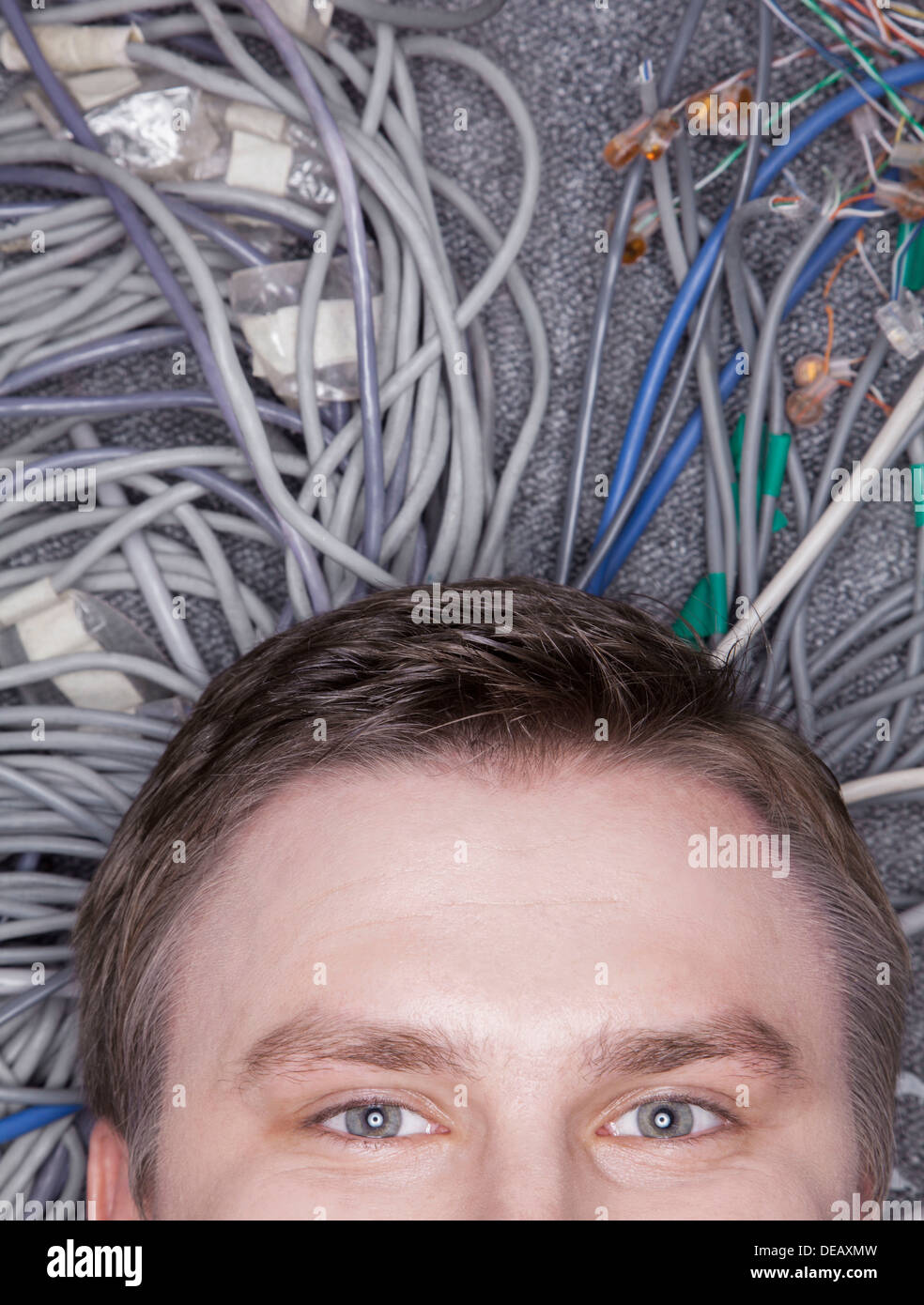 Businessman's face lying down on computer cables looking up, half Stock ...