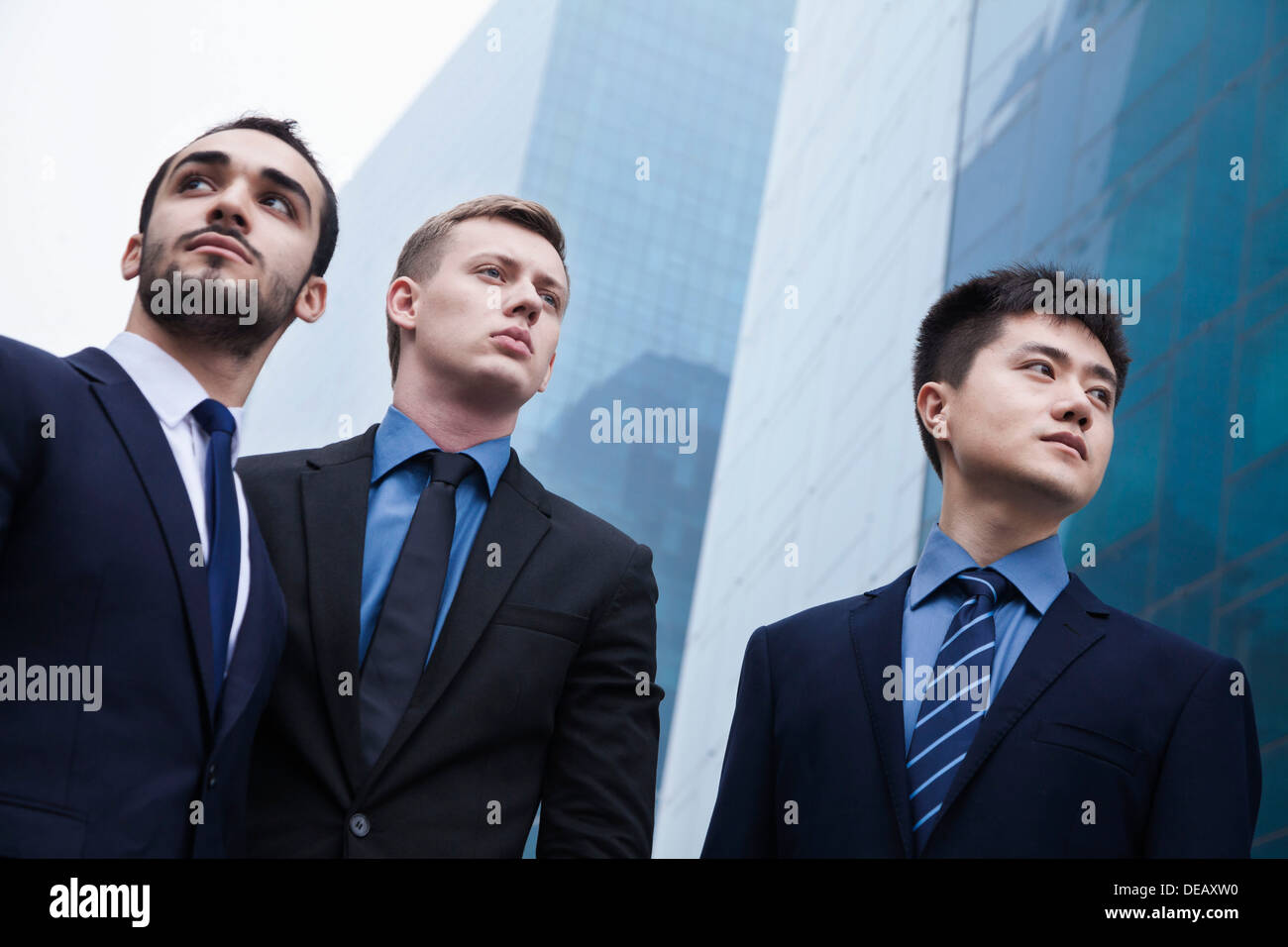 Portrait of three serious businessmen, outdoors, business district ...