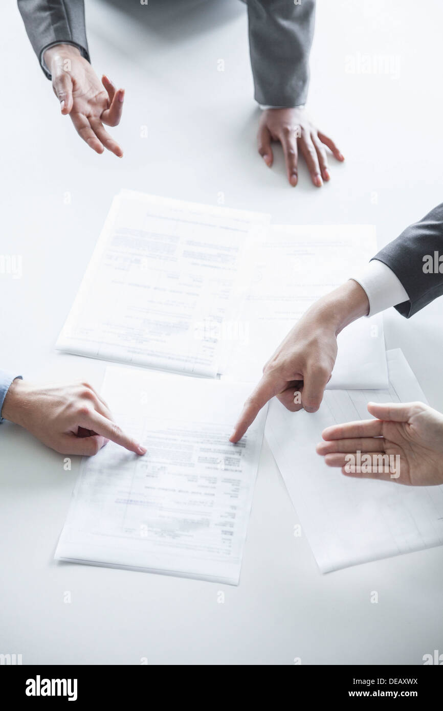 Four business people arguing and gesturing around a table during a ...