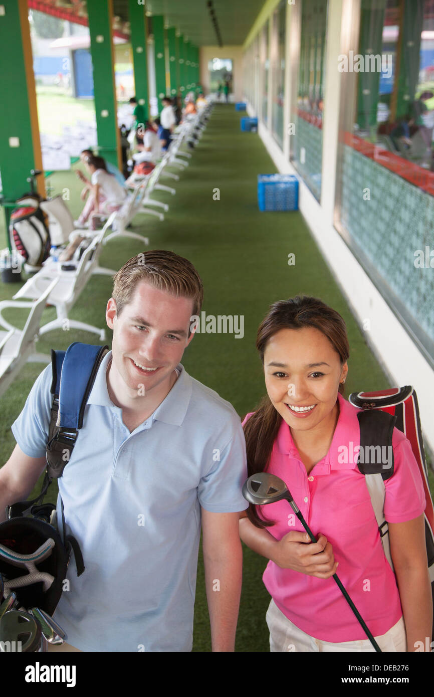 Young happy couple leaving the golf course with golf clubs and caddy ...