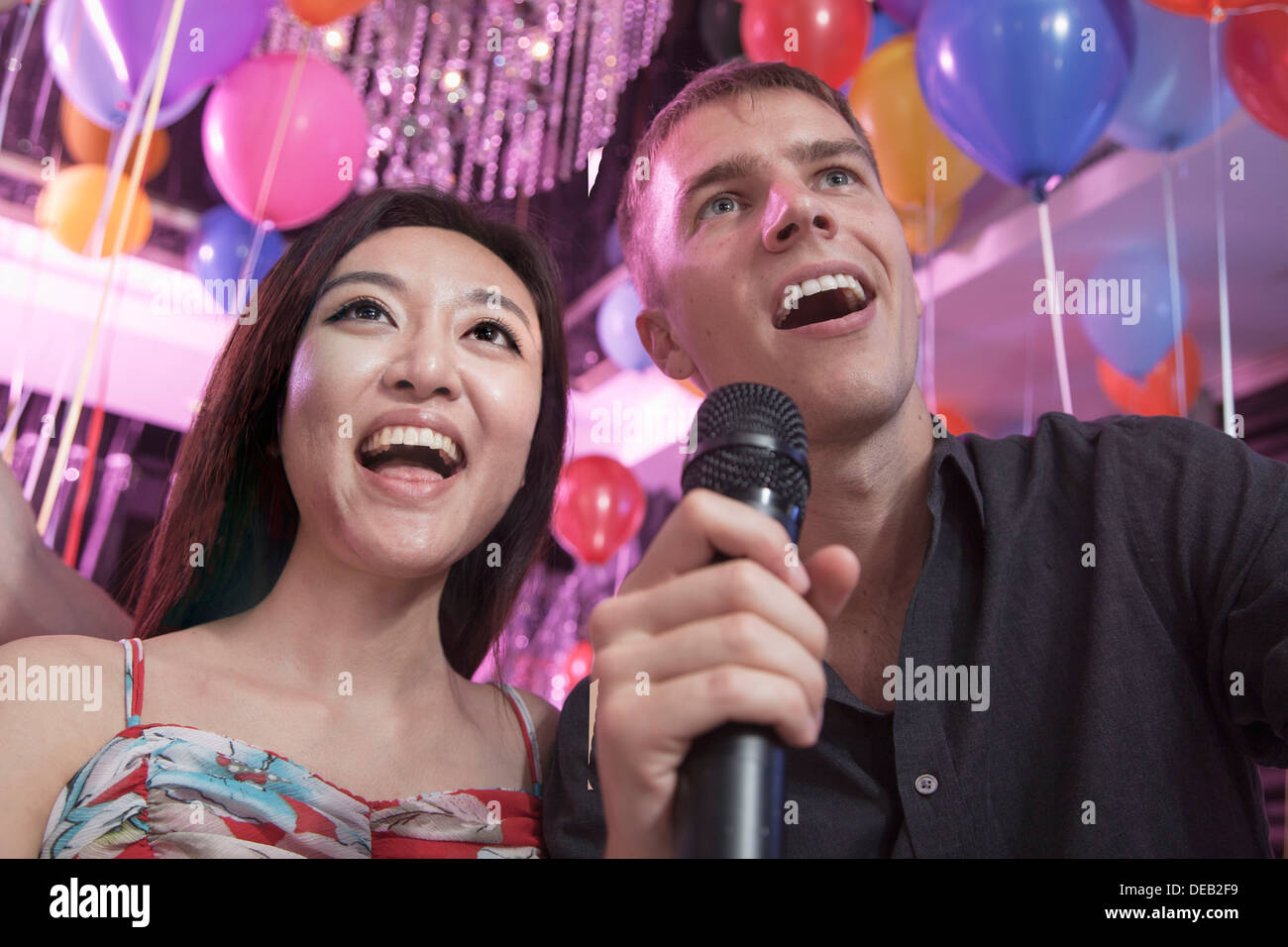 Two friends singing into a microphone together in a nightclub for ...