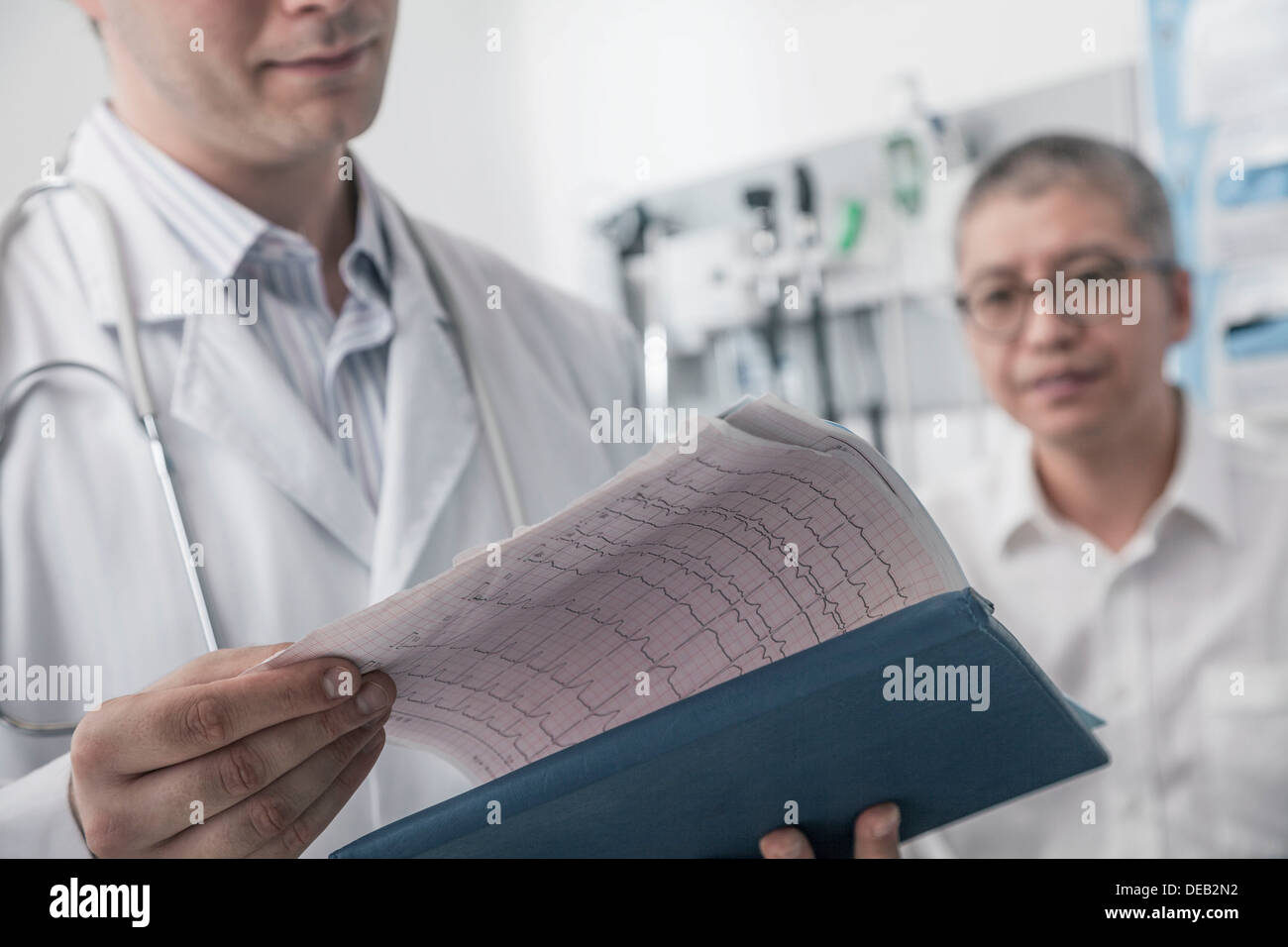 Doctor checking medical chart with patient in the background Stock ...