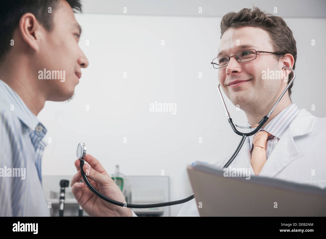 Smiling doctor checking heartbeat of a patient with a stethoscope Stock ...